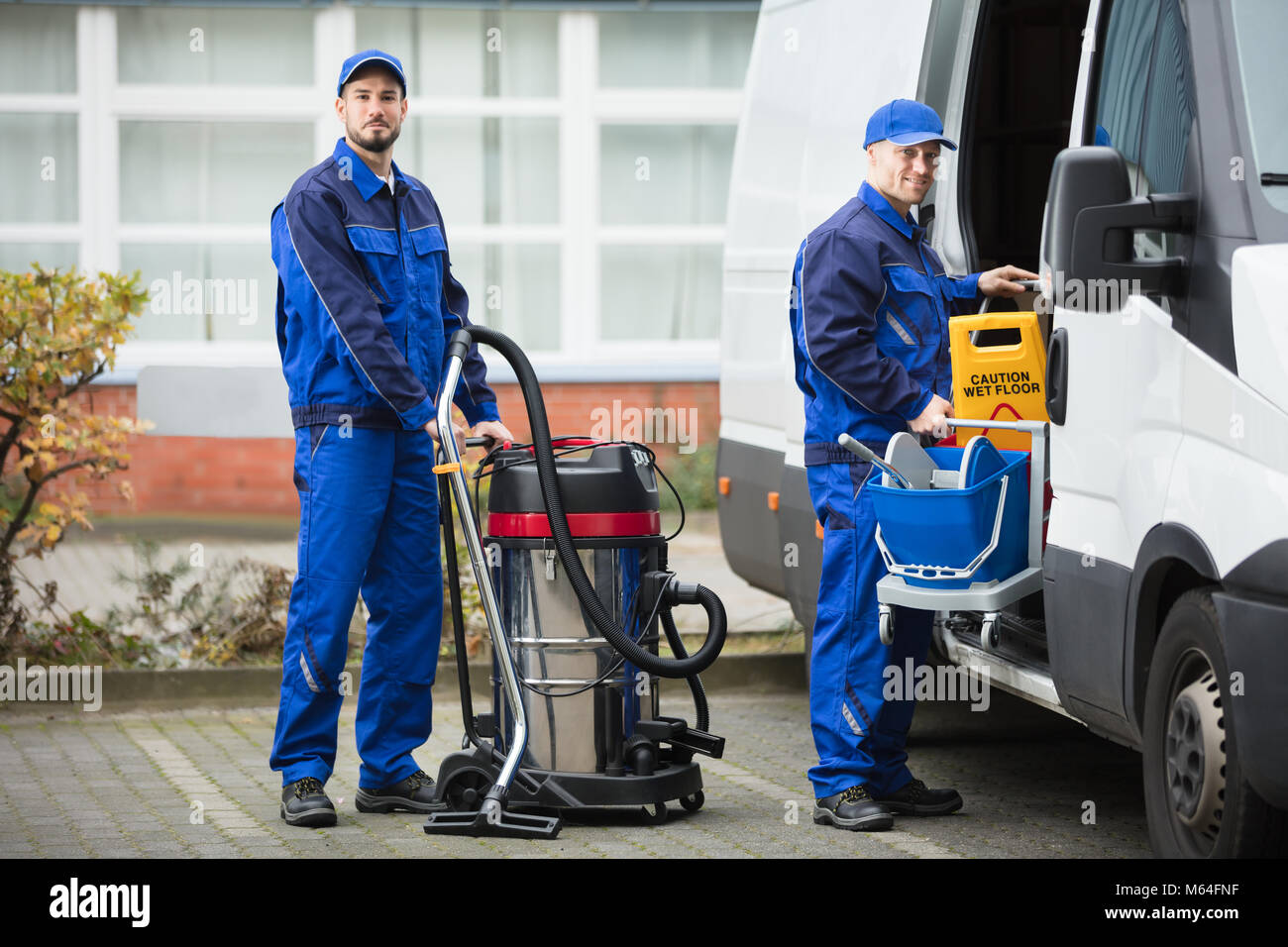 Two Young Male Janitor In Blue Uniform Unloading Cleaning Equipment ...