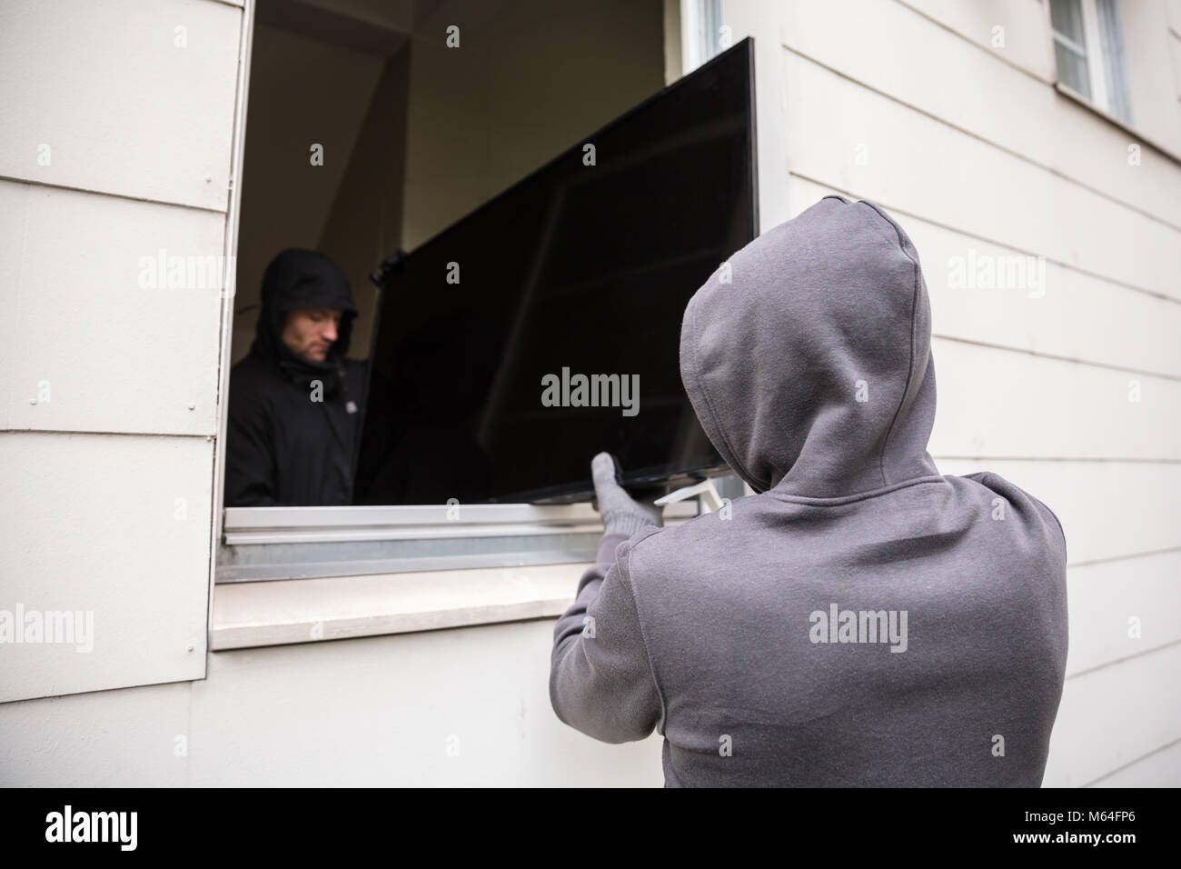 Male Robbers In Hoods Stealing Television Through House Window Stock ...