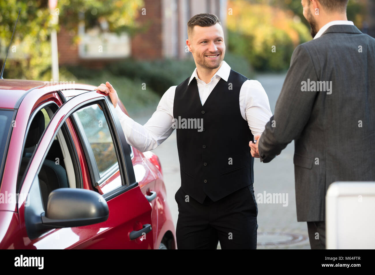 Smiling Young Male Valet And Businessperson Standing Near Red Car Stock ...