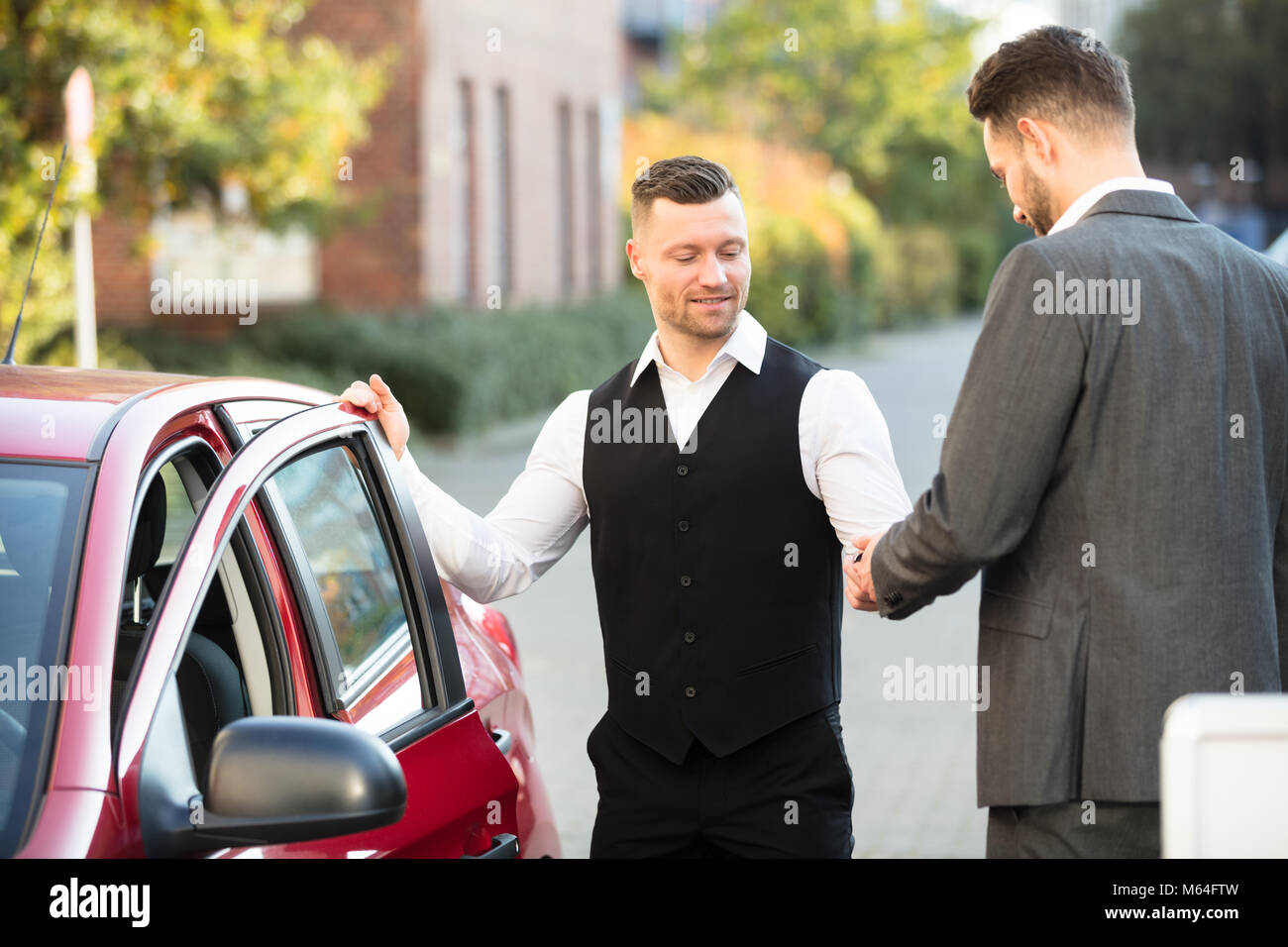 Smiling Young Male Valet And Businessperson Standing Near Red Car Stock ...