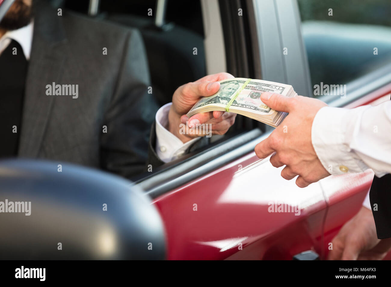 Businessman Sitting Inside Car Giving Bundle Of Banknote To Person ...
