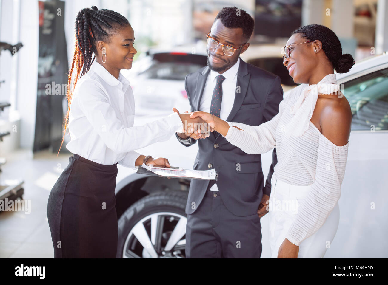 Customer buying a vehicle at car dealership. woman and man handshaking ...