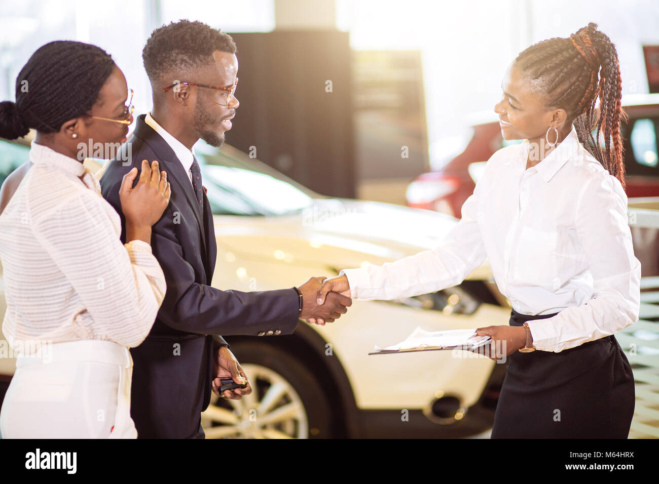 Customer buying a vehicle at car dealership. woman and man handshaking ...