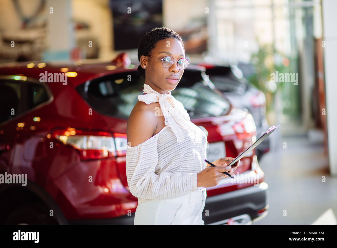 Professional female salesperson working in car dealership Stock Photo ...