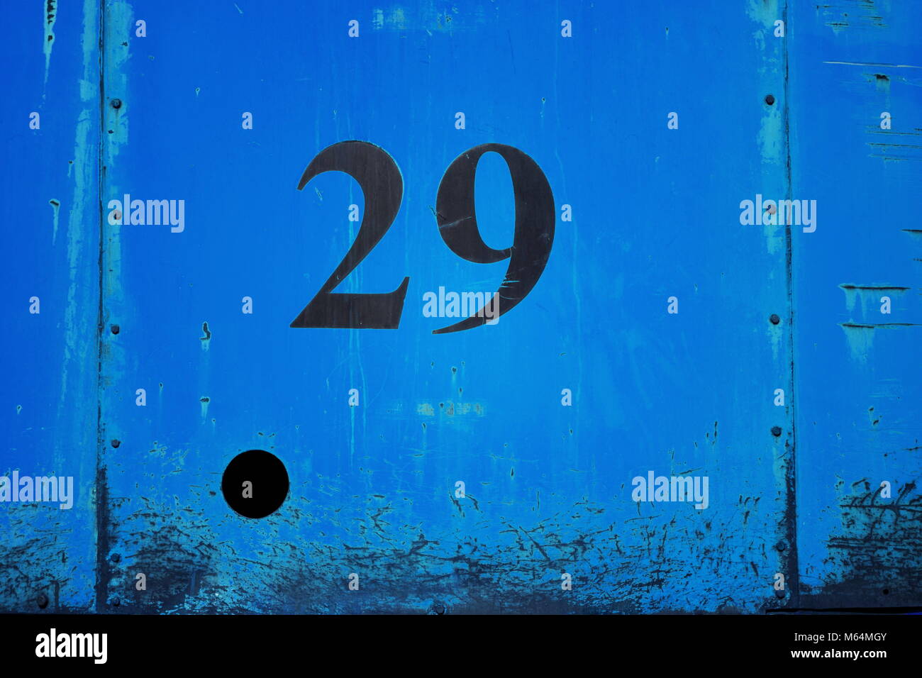 Number 29 on rusty blue metal sheet plate with hole Stock Photo - Alamy