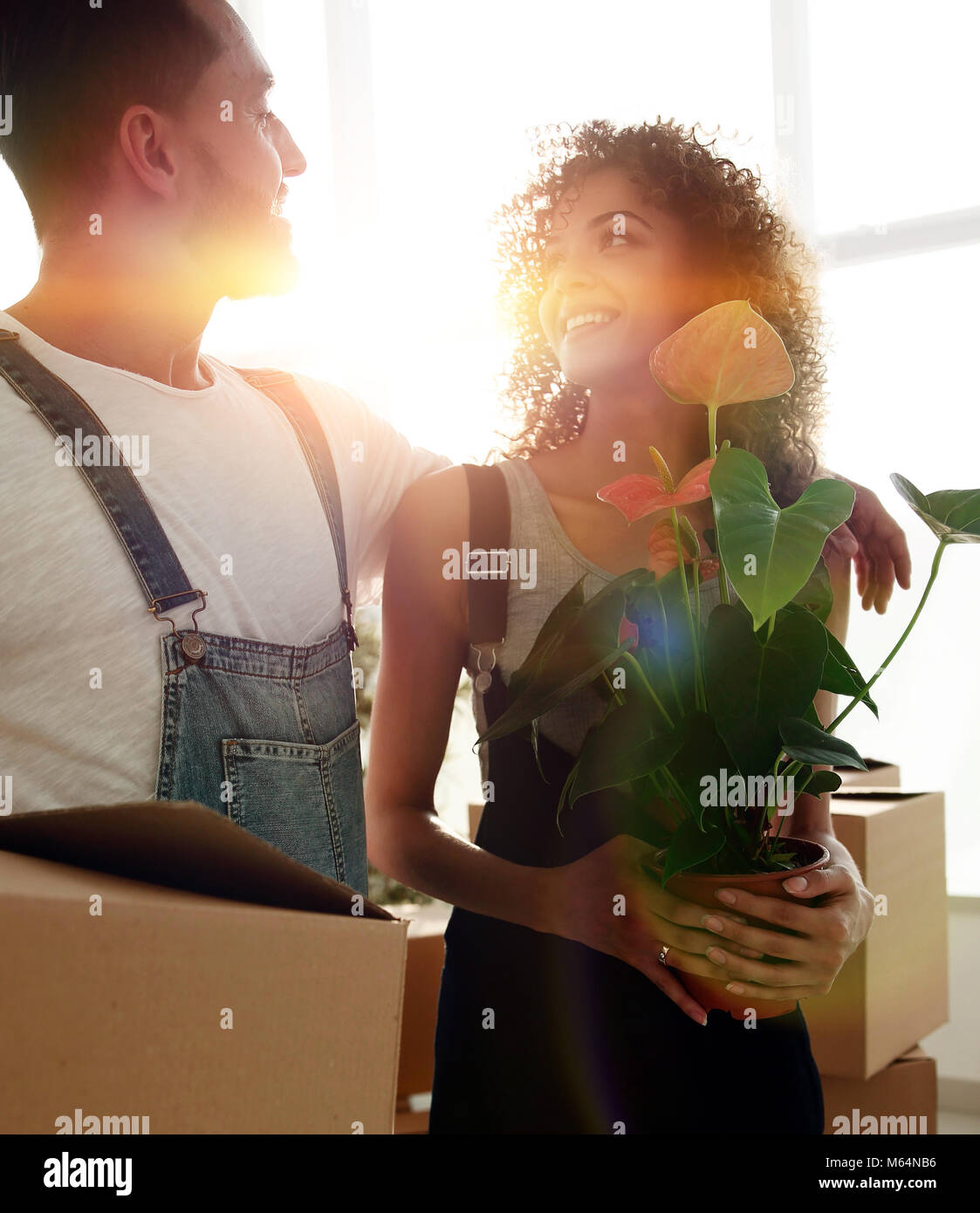 Close-up of a beautiful young couple is carrying things into a new home ...