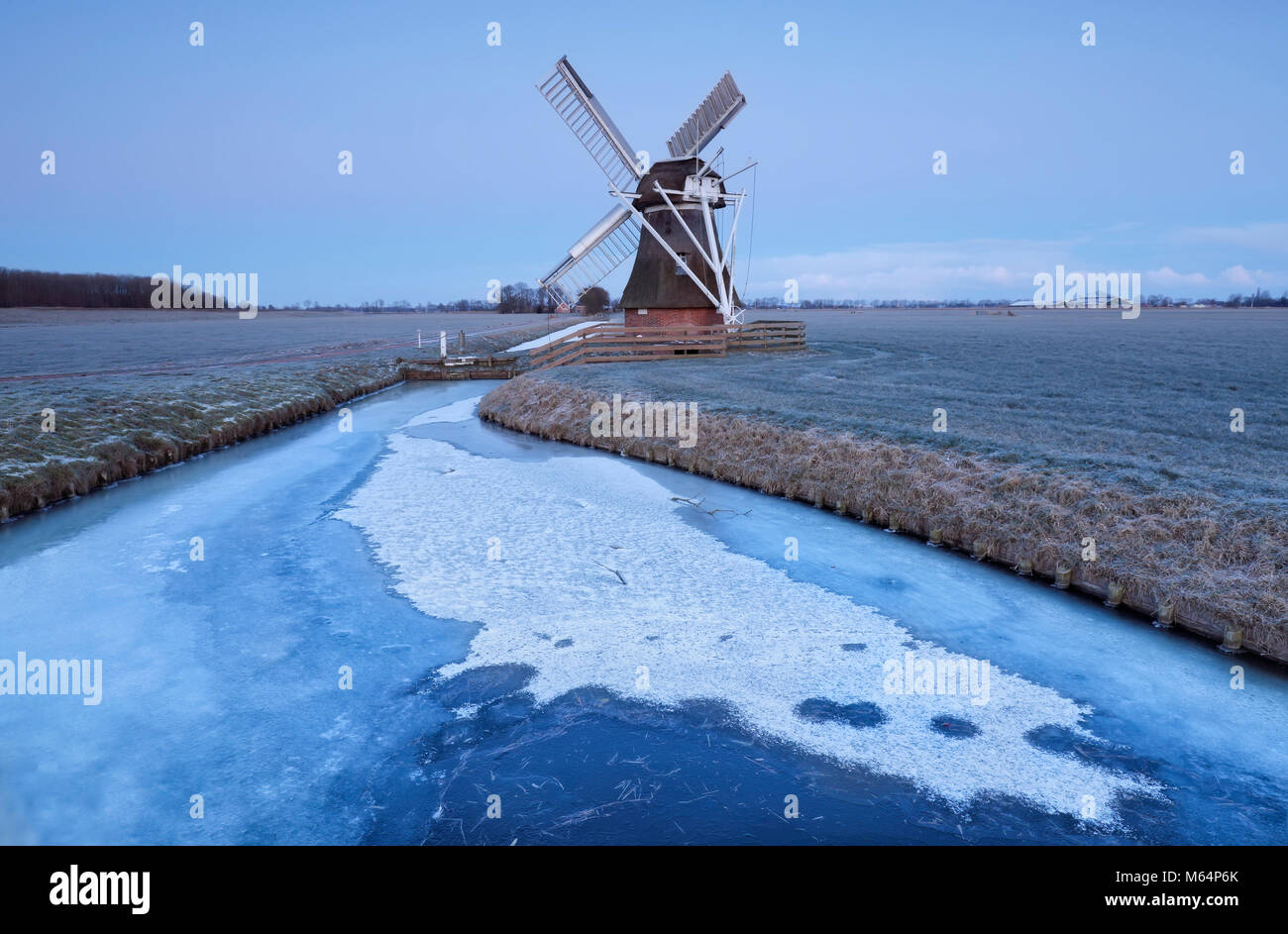 Dutch windmill in dusk by frozen river in winter, Holland Stock Photo ...