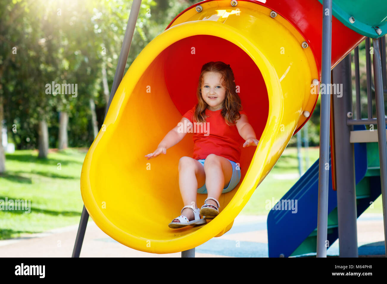Kids climbing and sliding on outdoor playground. Children play in sunny ...