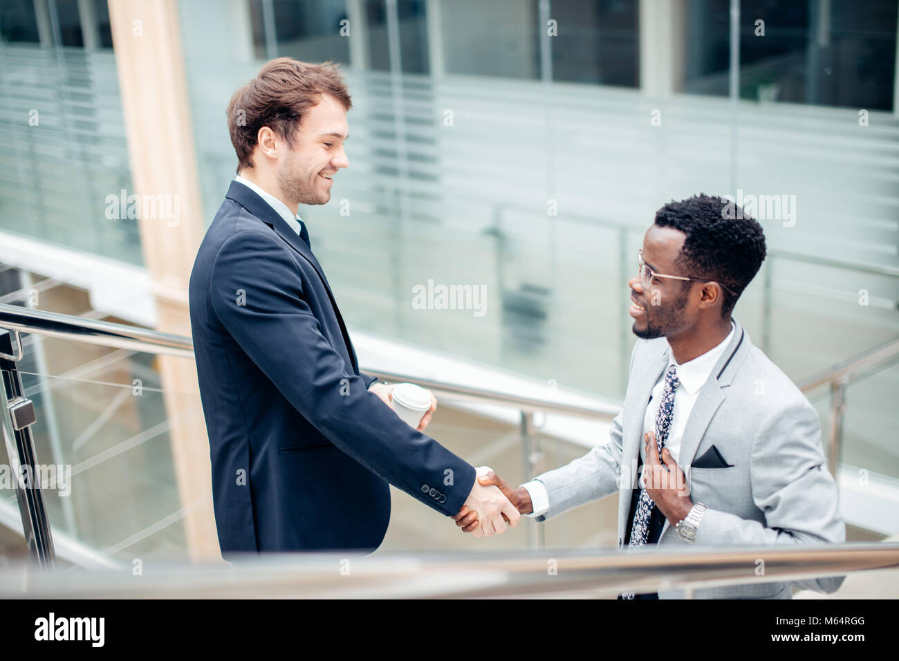 two multiracial businessmen handshaking in modern office for end of ...