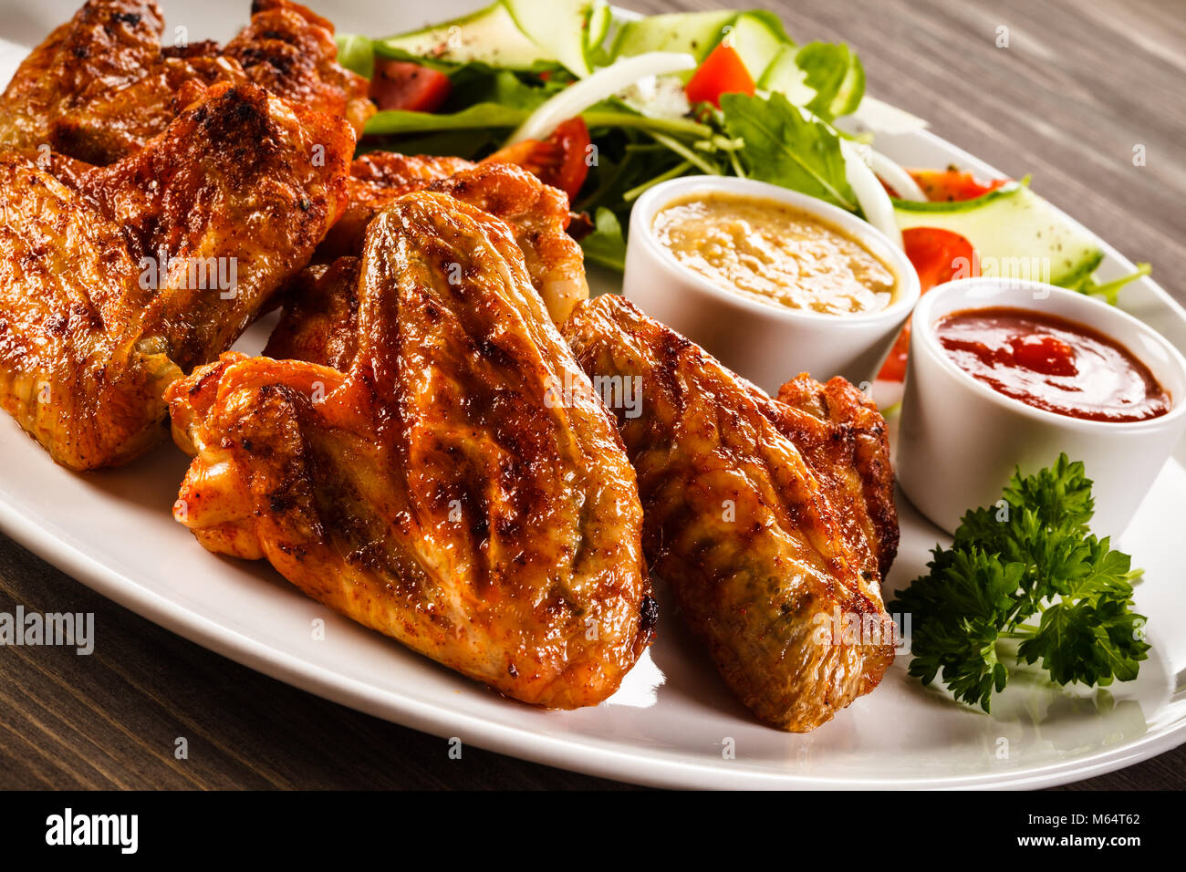 Grilled chicken wigs and vegetables on wooden table Stock Photo - Alamy