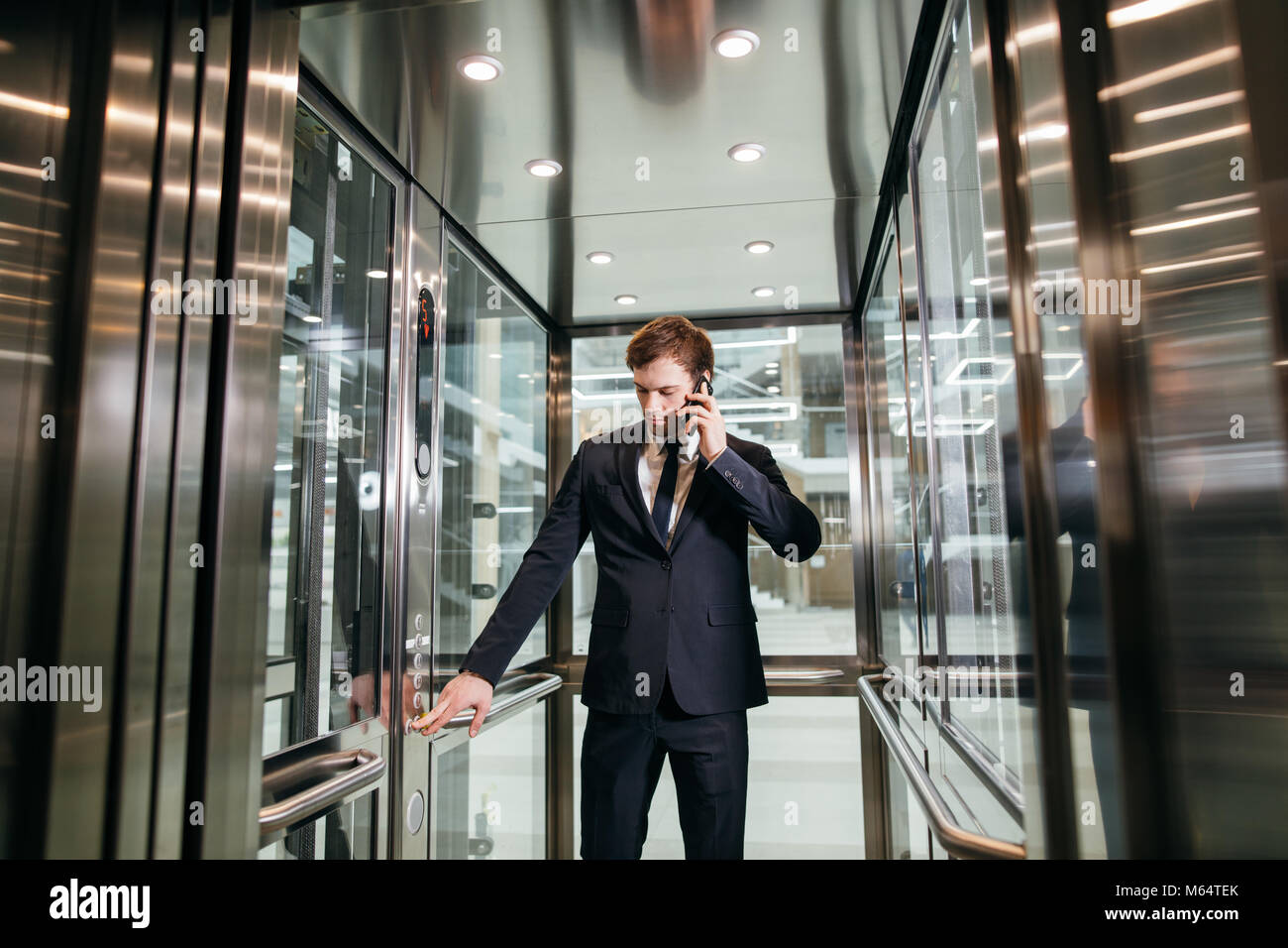 Business man walking while talking on mobile phone on his way to work ...