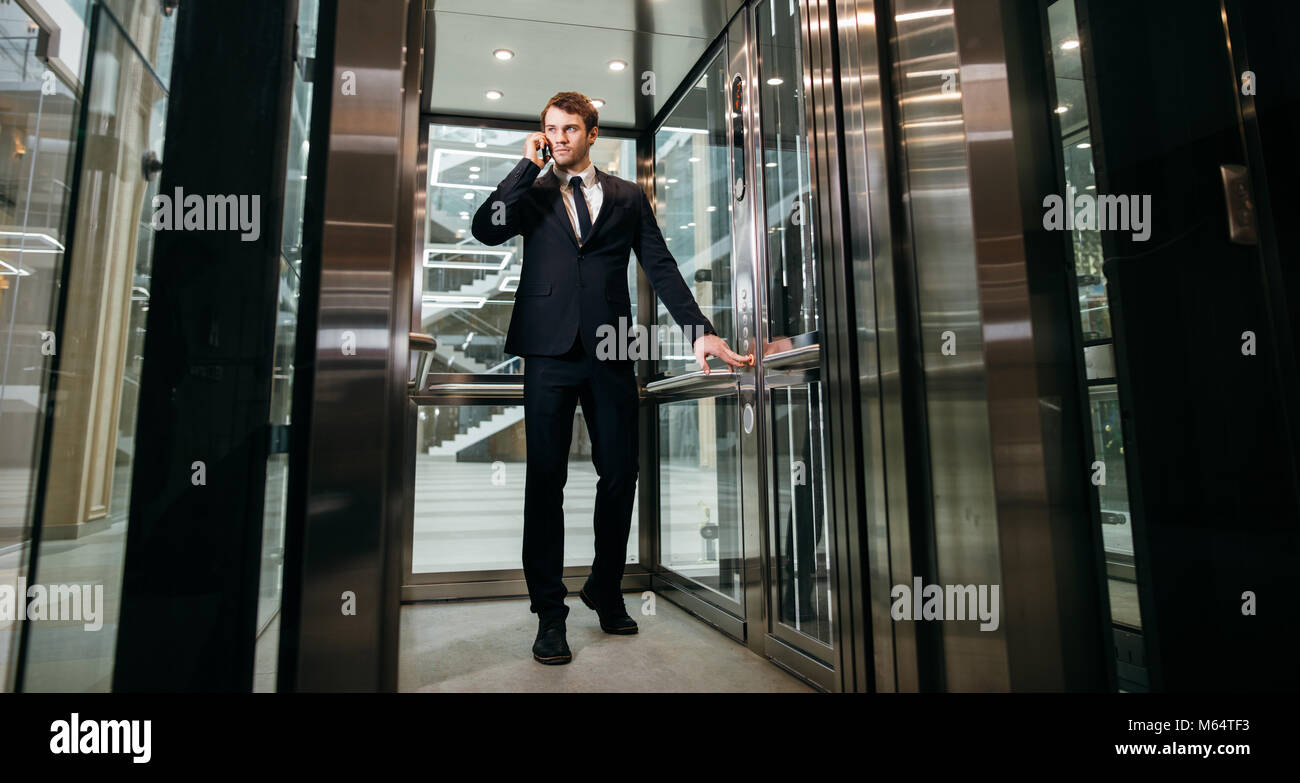 Business man walking while talking on mobile phone on his way to work ...