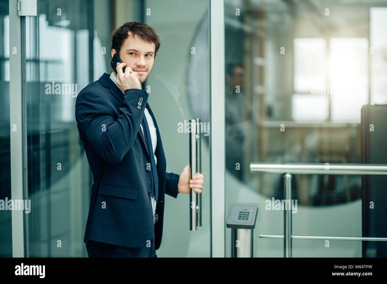 Business man walking while talking on mobile phone on his way to work ...