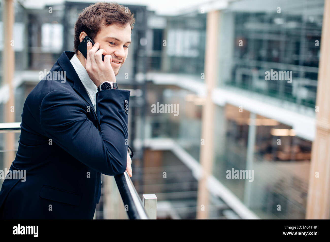 Business man walking while talking on mobile phone on his way to work ...