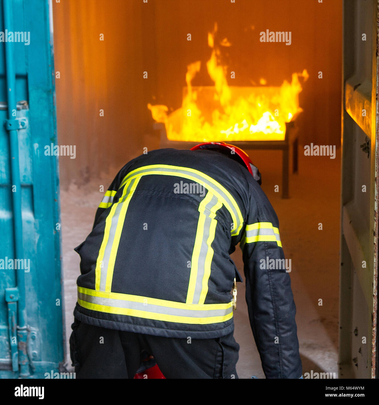 Fireman during training. Fire extinguisher. Golden yellow flames / fire ...