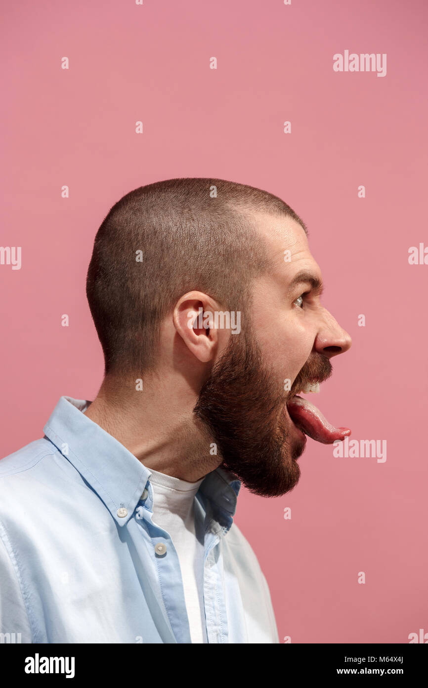 The young emotional angry, crazy man on pink studio background Stock ...