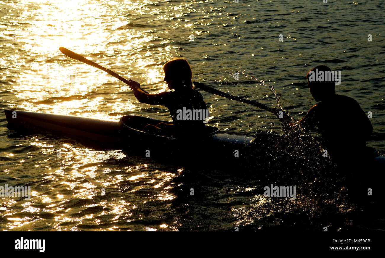 Young people rowing on the river at sunset Stock Photo - Alamy