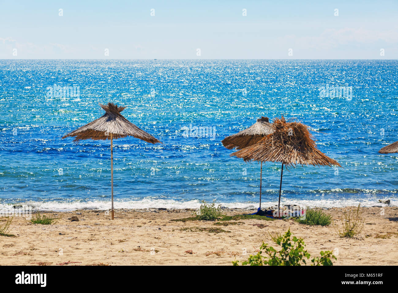 Straw beach umbrellas. Straw parasols. Sunny day on the beach Stock ...