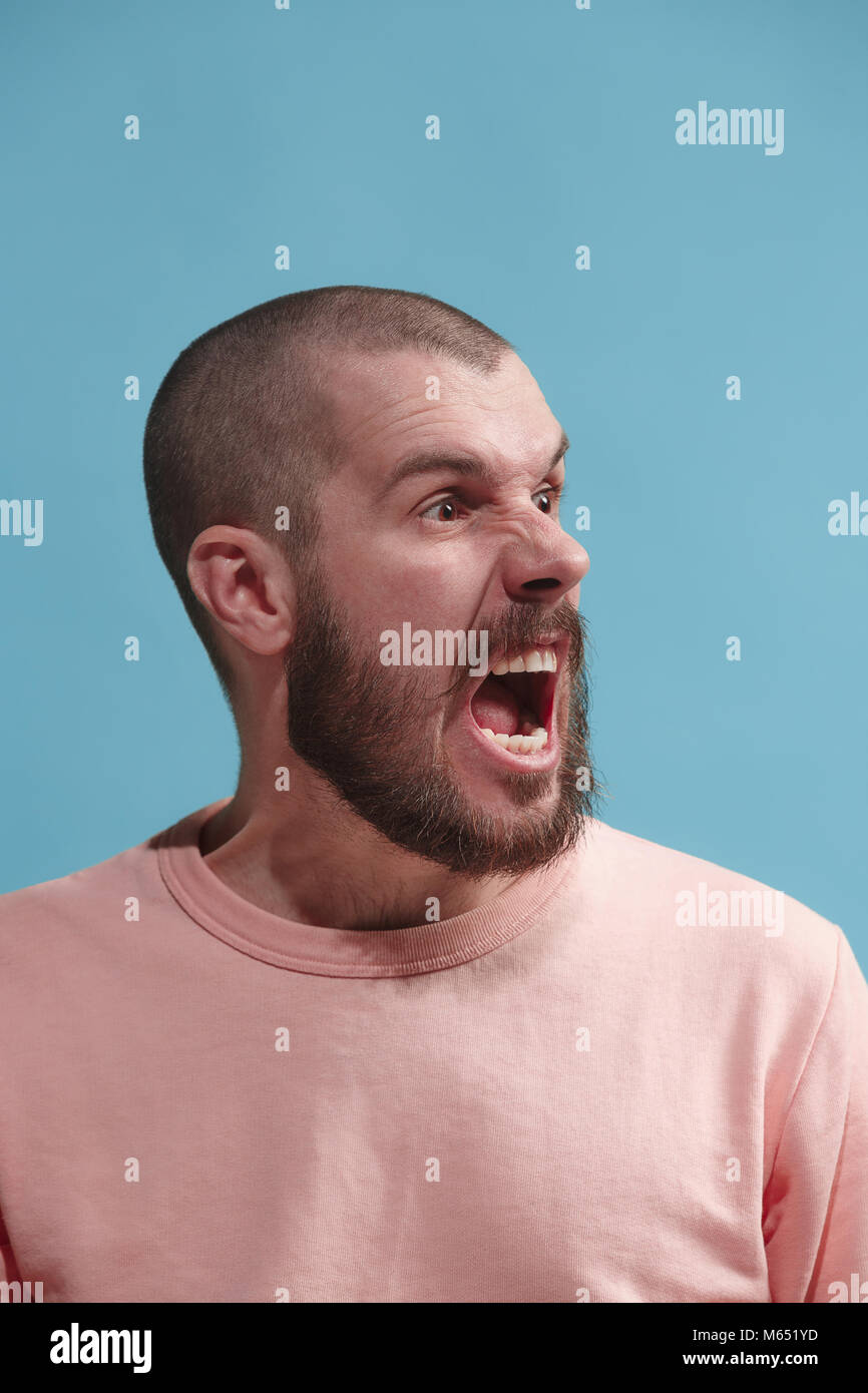 The young emotional angry man screaming on blue studio background Stock ...