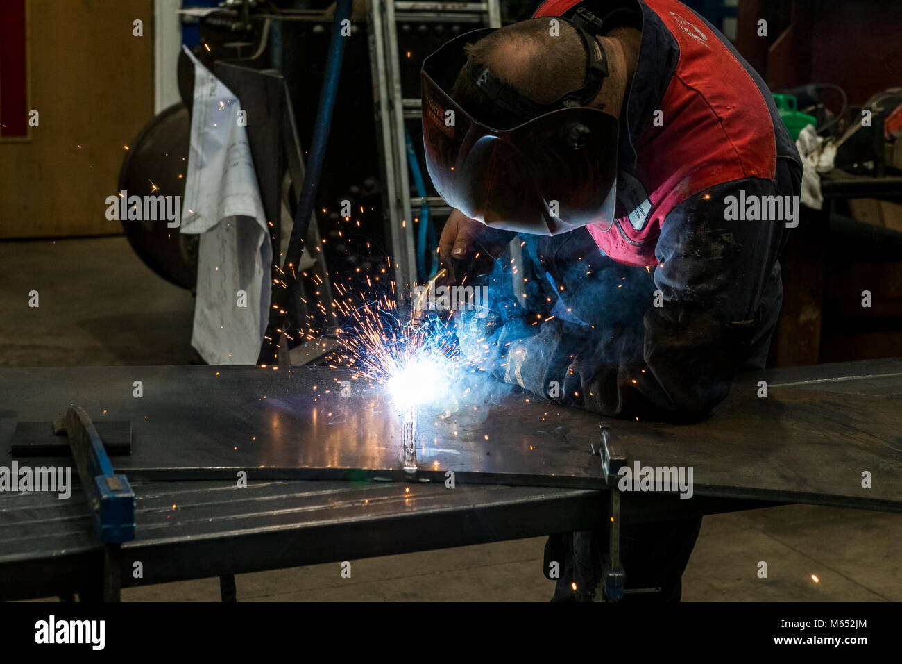 A welders protective visor lit up by the power of the welding gun ...