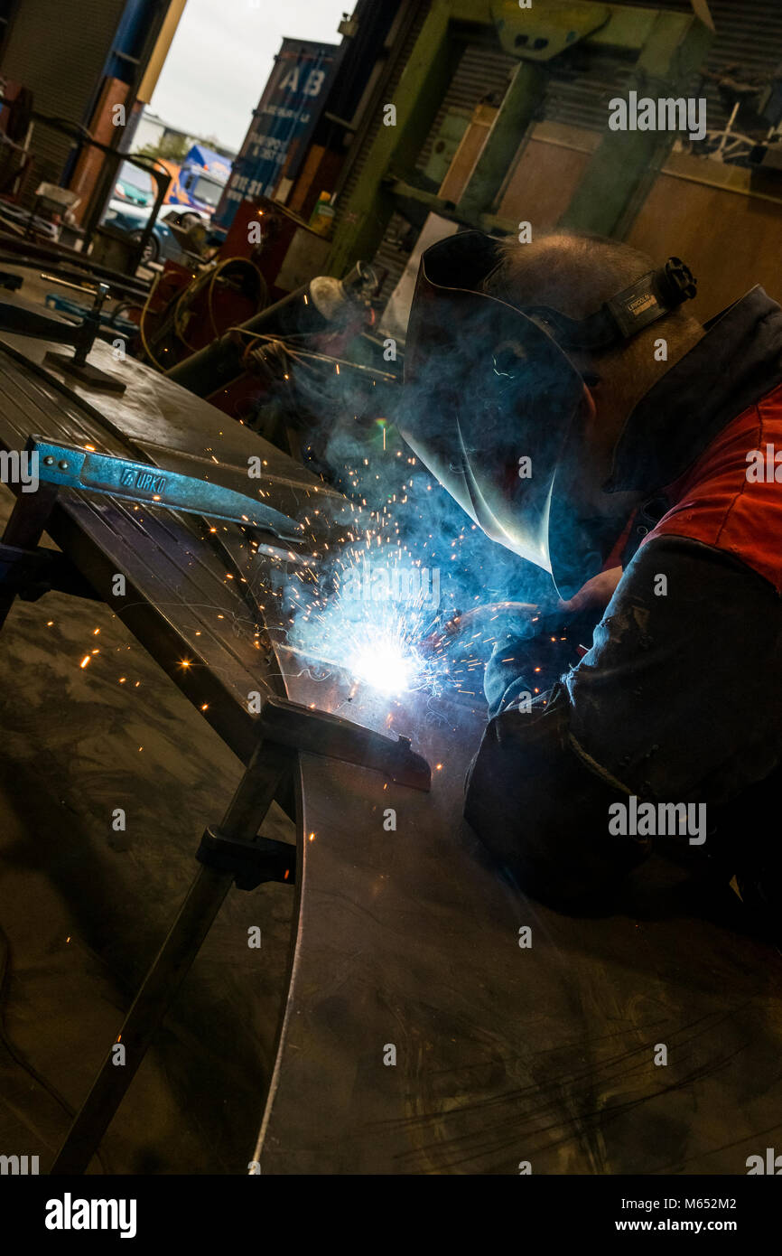 A welders protective visor lit up by the power of the welding gun ...