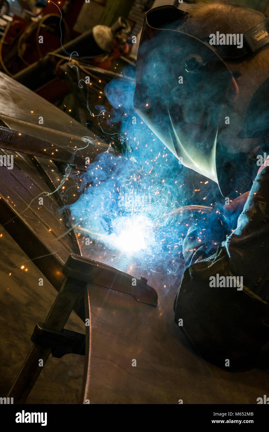 A welders protective visor lit up by the power of the welding gun ...