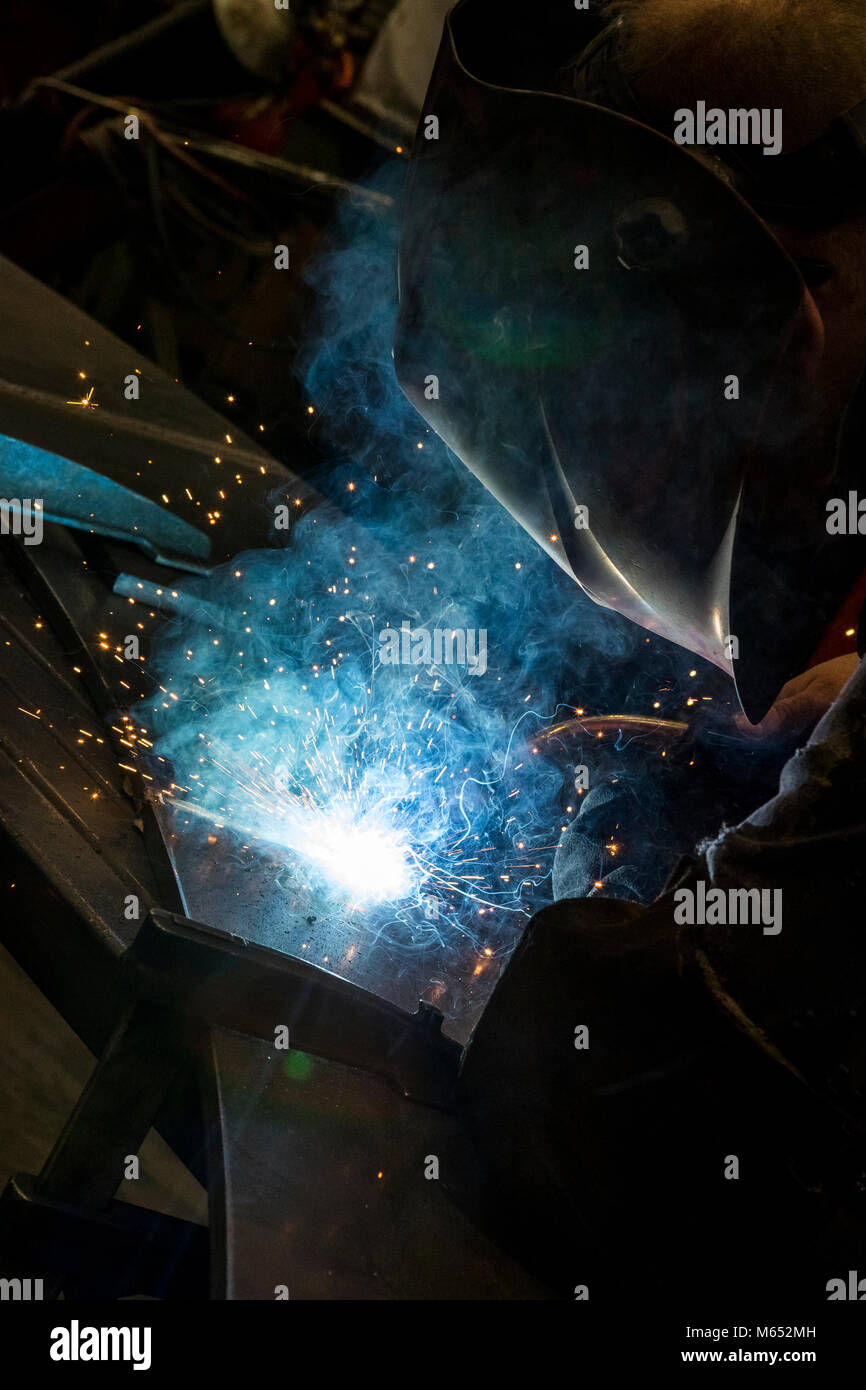 A welders protective visor lit up by the power of the welding gun ...