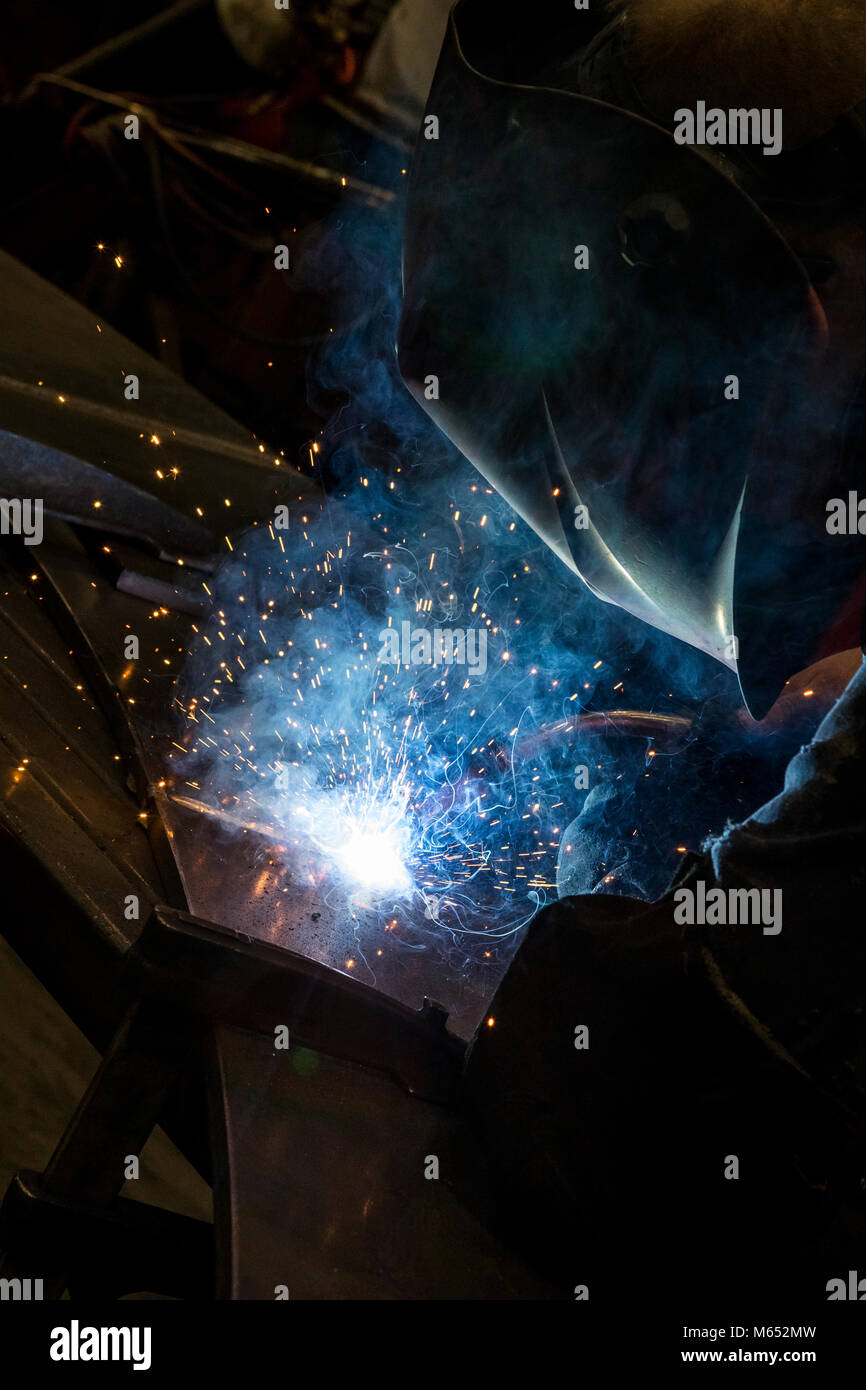 A welders protective visor lit up by the power of the welding gun ...