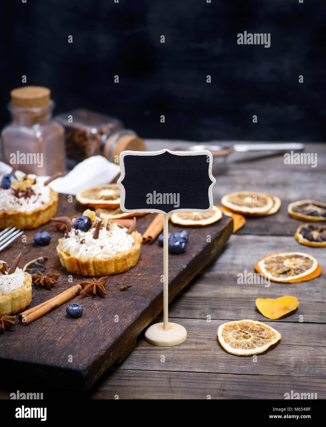 Empty wooden sign with a black surface on a table with cakes, vintage ...