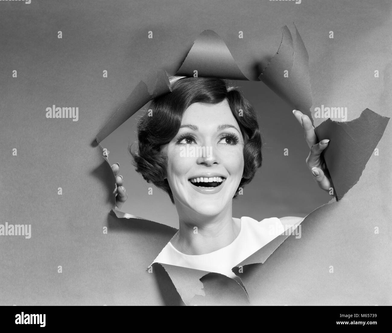 1960s 1960s WOMAN SMILING LOOKING BREAKING THROUGH TORN PAPER - g7074 ...
