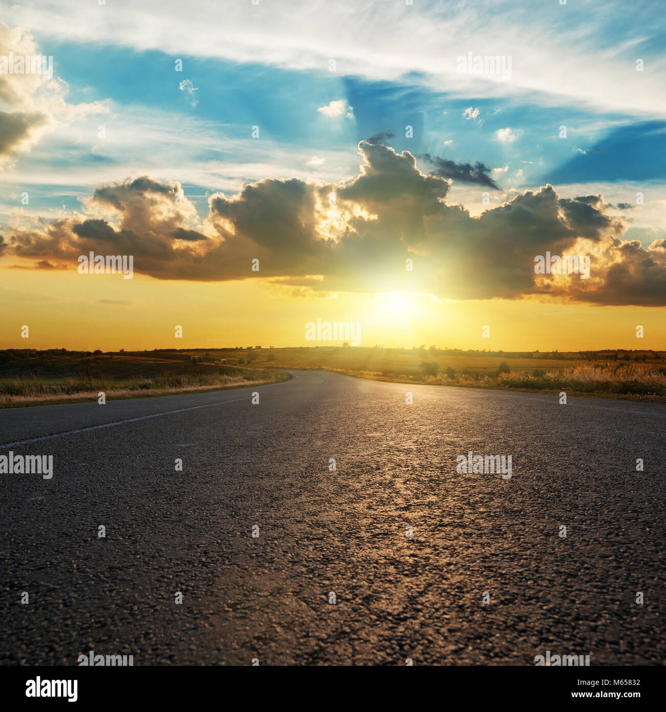 Dramatic clouds and low sun in sunset over asphalt road Stock Photo - Alamy