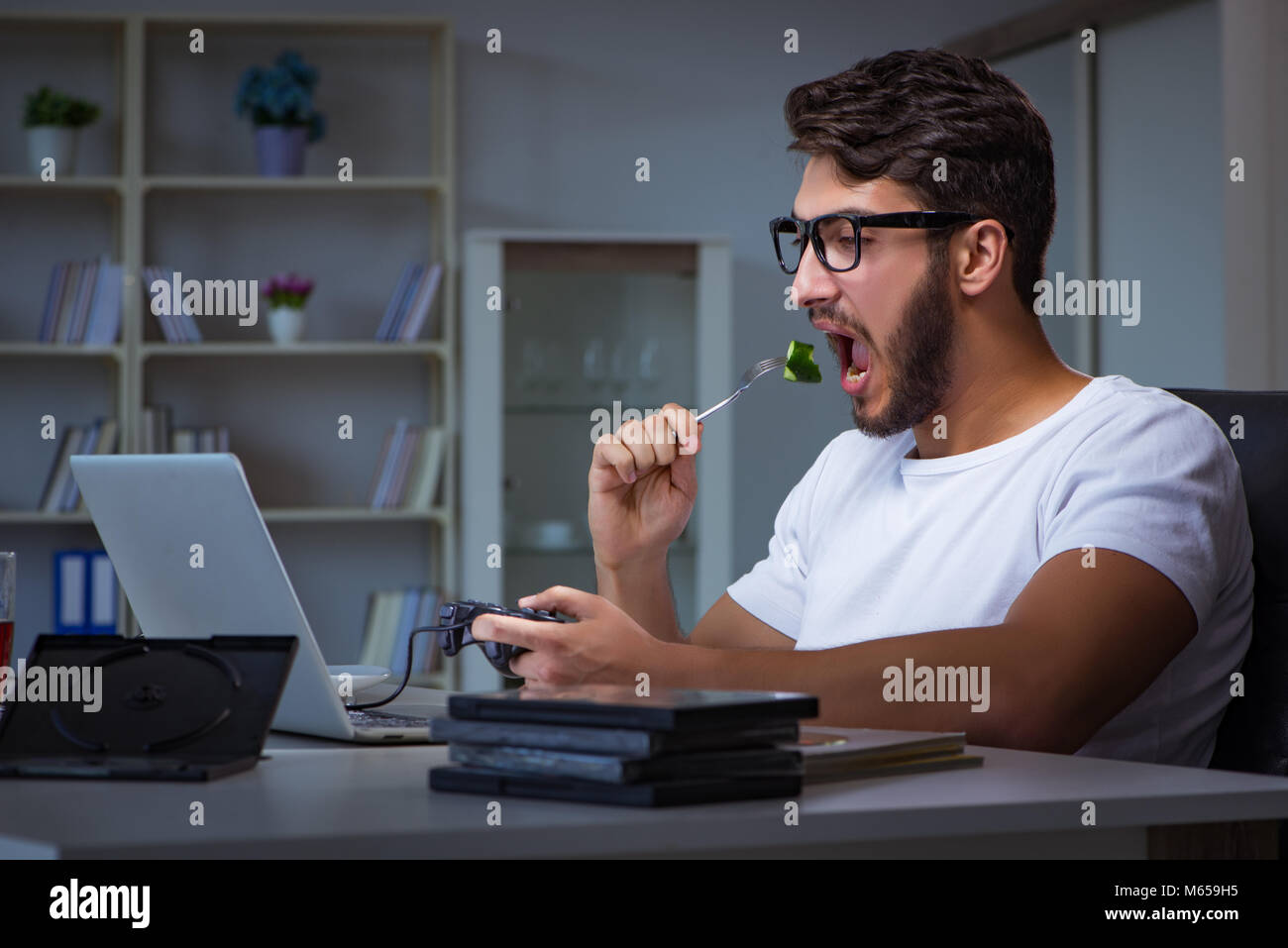 Young man playing games long hours late in the office Stock Photo - Alamy