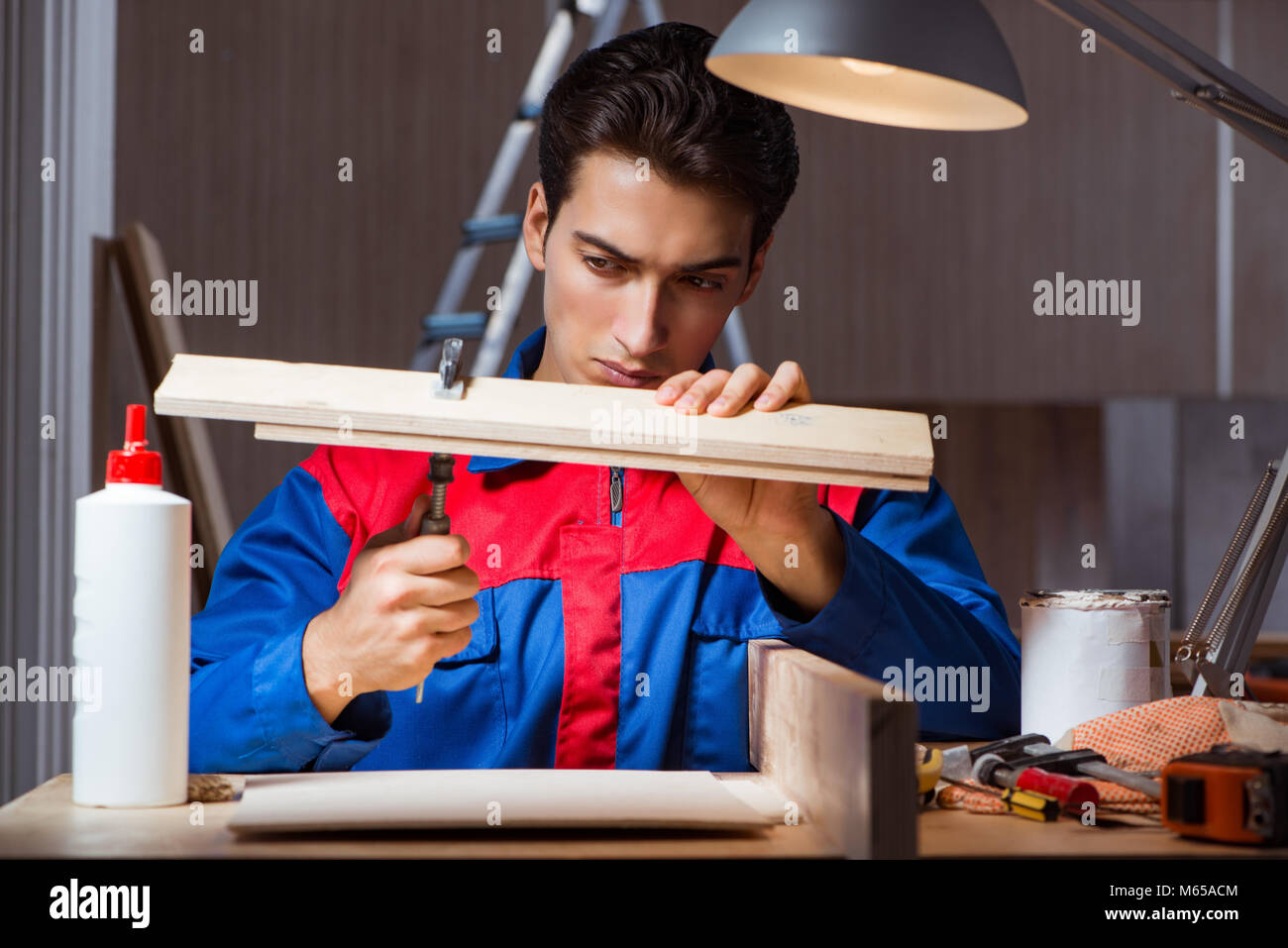 Young man gluing wood pieces together in DIY concept Stock Photo - Alamy