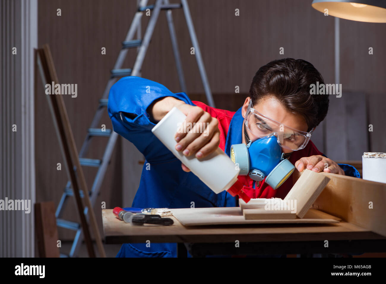 Young man gluing wood pieces together in DIY concept Stock Photo - Alamy