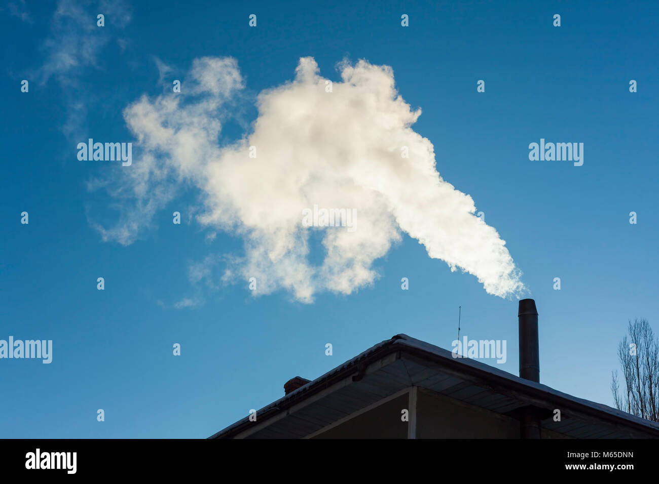 smoke coming out of house chimney. blue sky background Stock Photo - Alamy