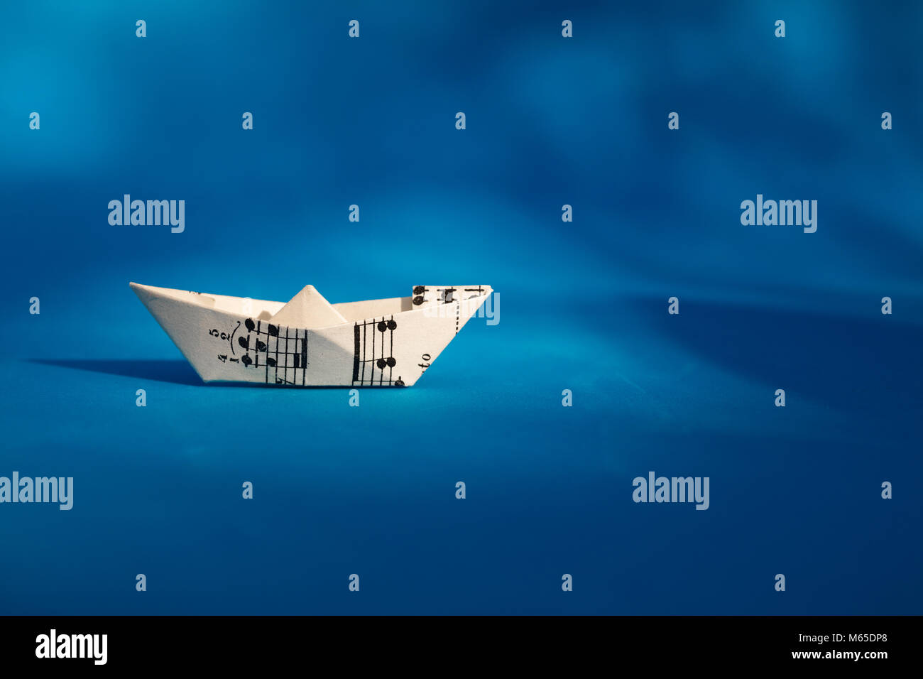 Paper boat made of musical score sheet in blue background Stock Photo ...