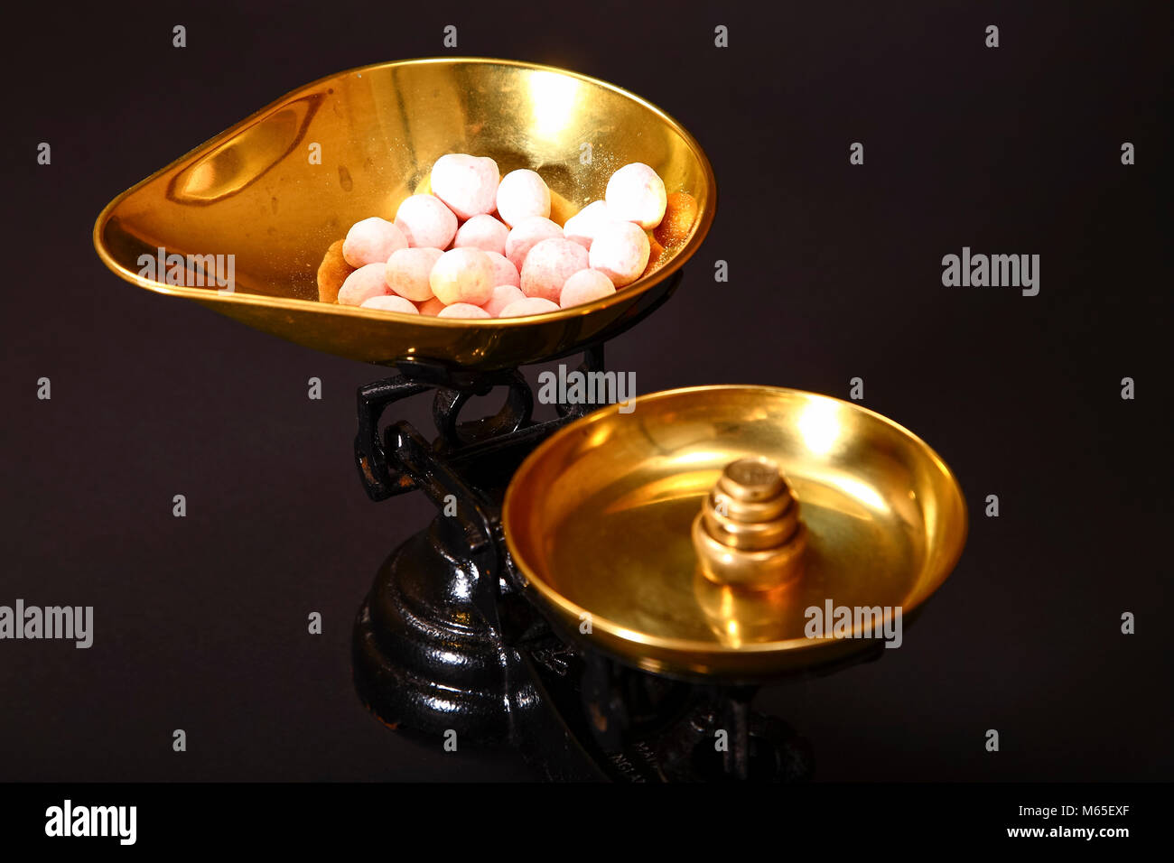 Sweets being weighed in vintage scales isolated on a black background ...