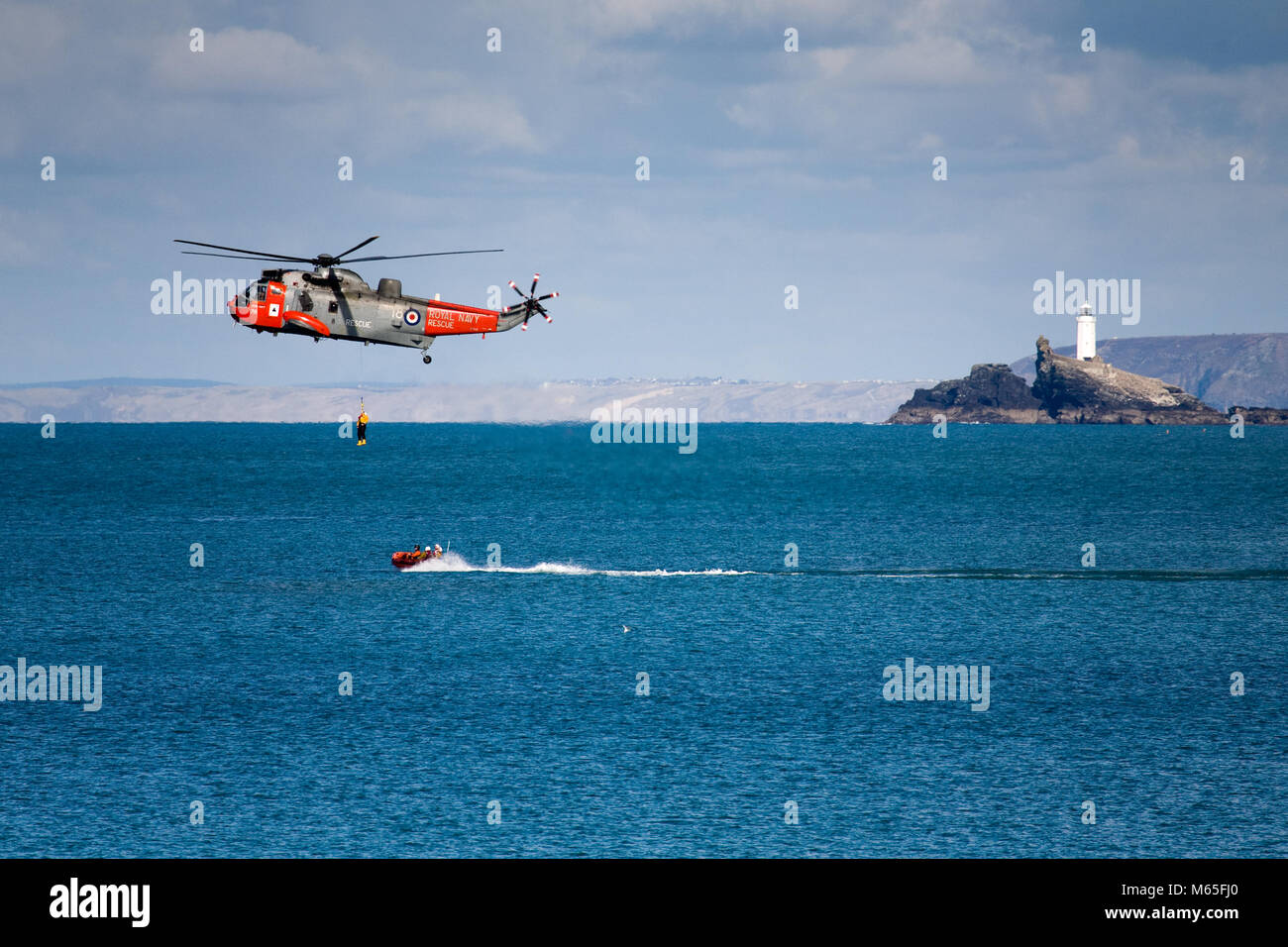 Rescue helicopter over zodiac winching person to safety with lighthouse ...