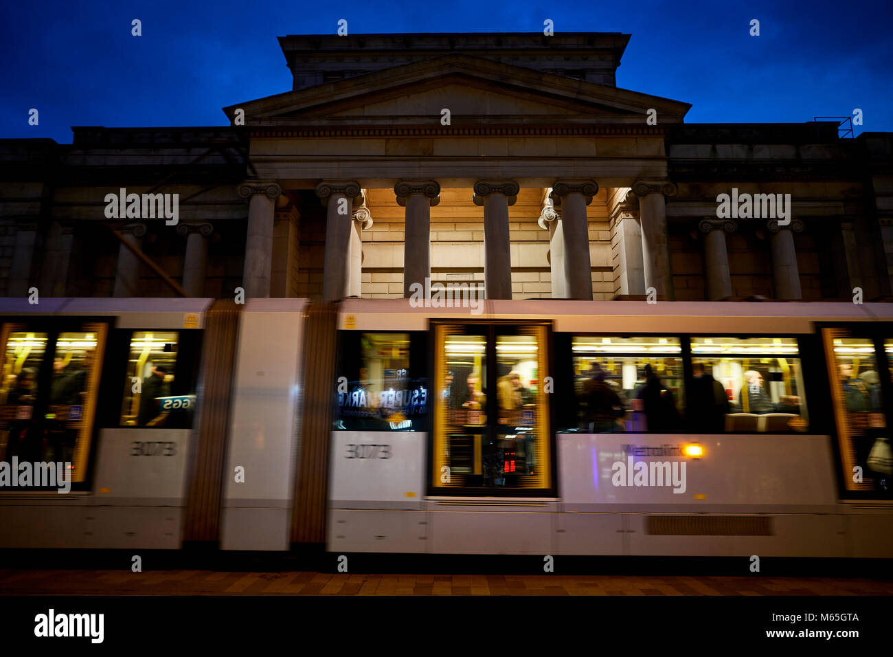 At night a Metrolink tram passing Manchester Art Gallery on Lower ...