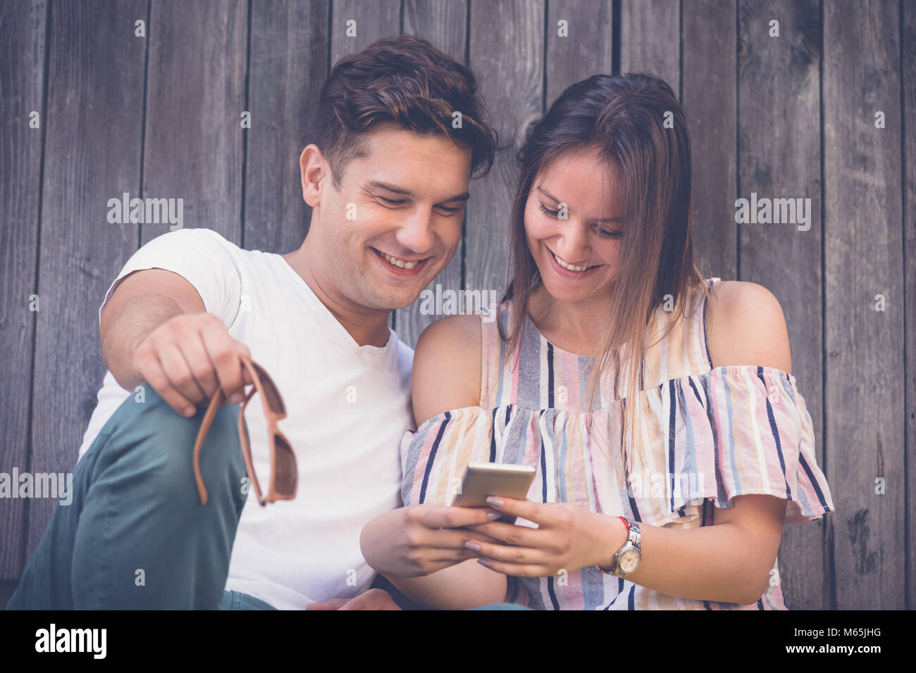 Beautiful couple in love sharing smart phone to watch media content ...