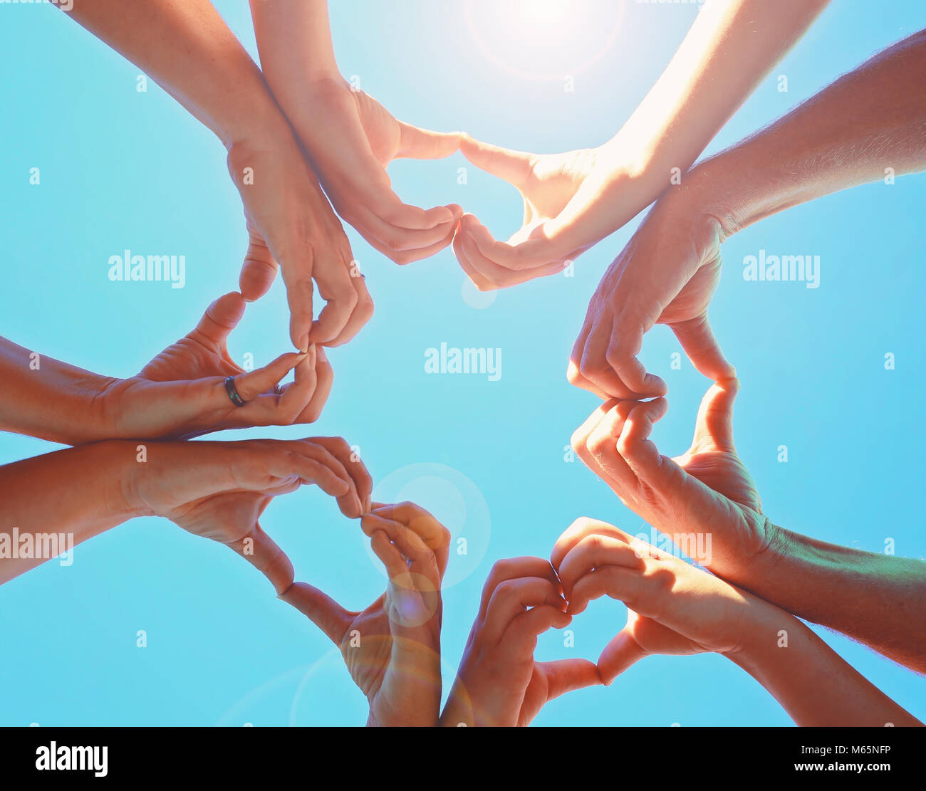 overhead view of a group of people making heart shapes with their hands ...
