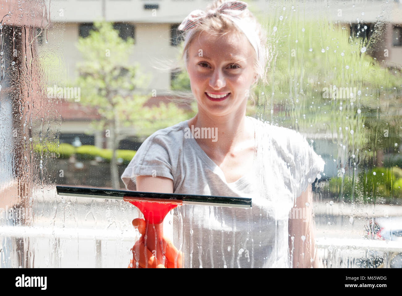 Cleaning woman washing windows using a squeegee to wash a window Stock ...