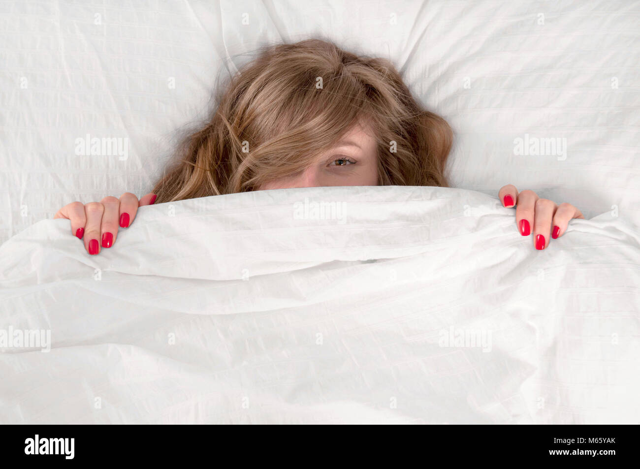 Woman hiding under blanket on bed at bedroom Stock Photo - Alamy