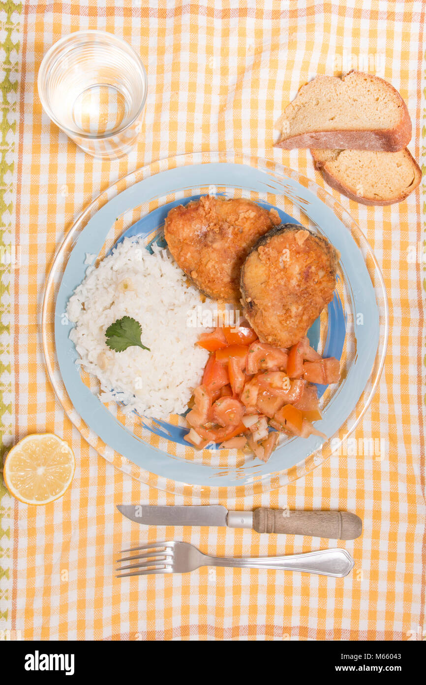 Fried hake fish with rice and tomato salad Stock Photo - Alamy
