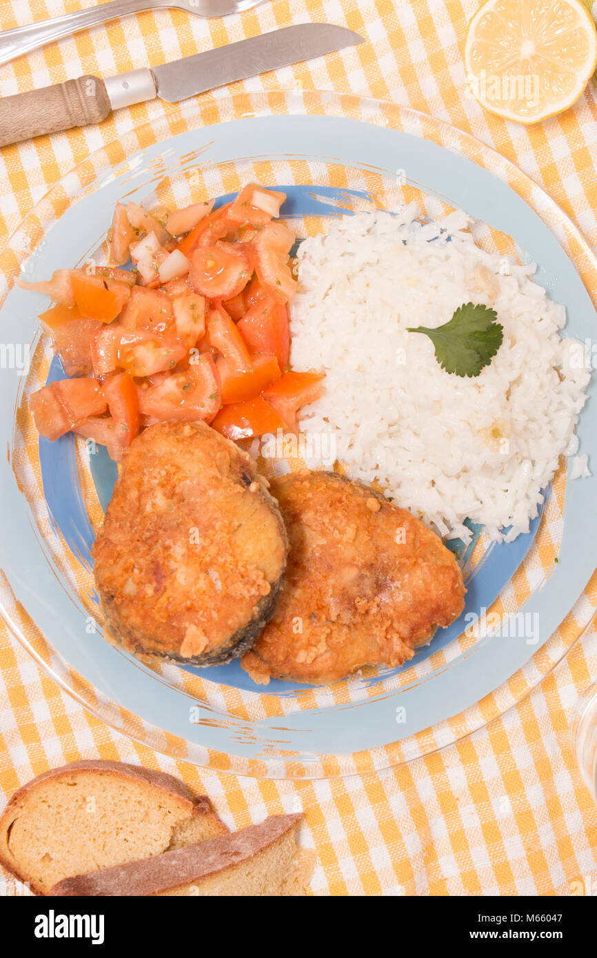 Fried hake fish with rice and tomato salad Stock Photo - Alamy