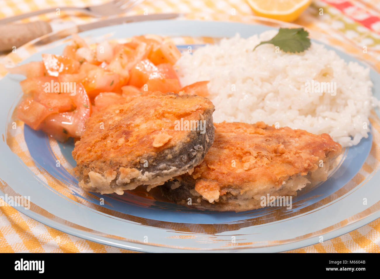 Fried hake fish with rice and tomato salad Stock Photo - Alamy