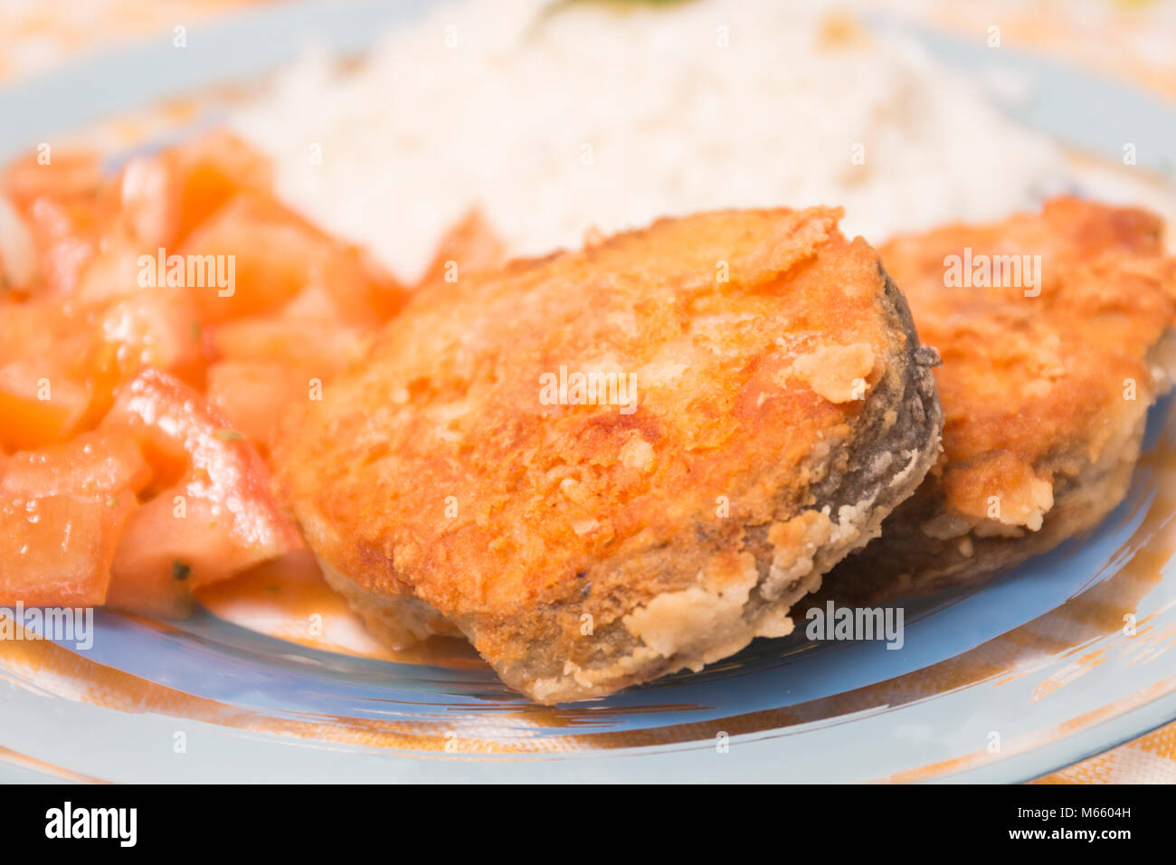 Fried hake fish with rice and tomato salad Stock Photo - Alamy