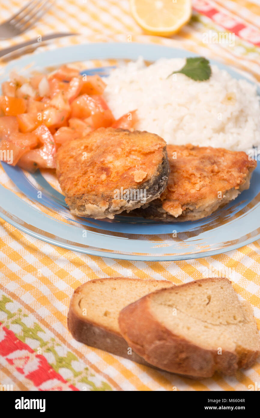 Fried hake fish with rice and tomato salad Stock Photo - Alamy