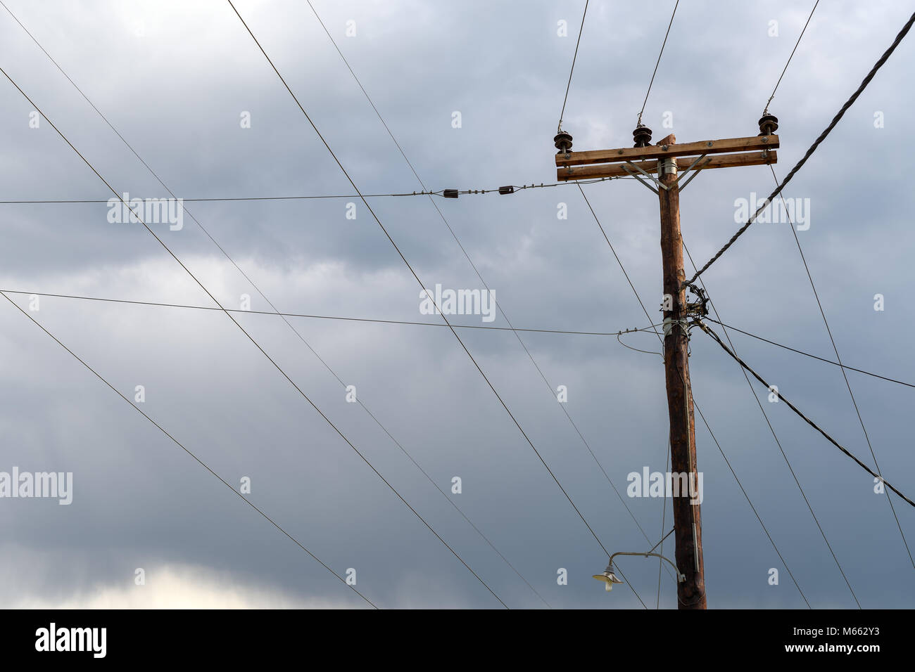 Old wooden electric pillar with connections and power lines going into ...