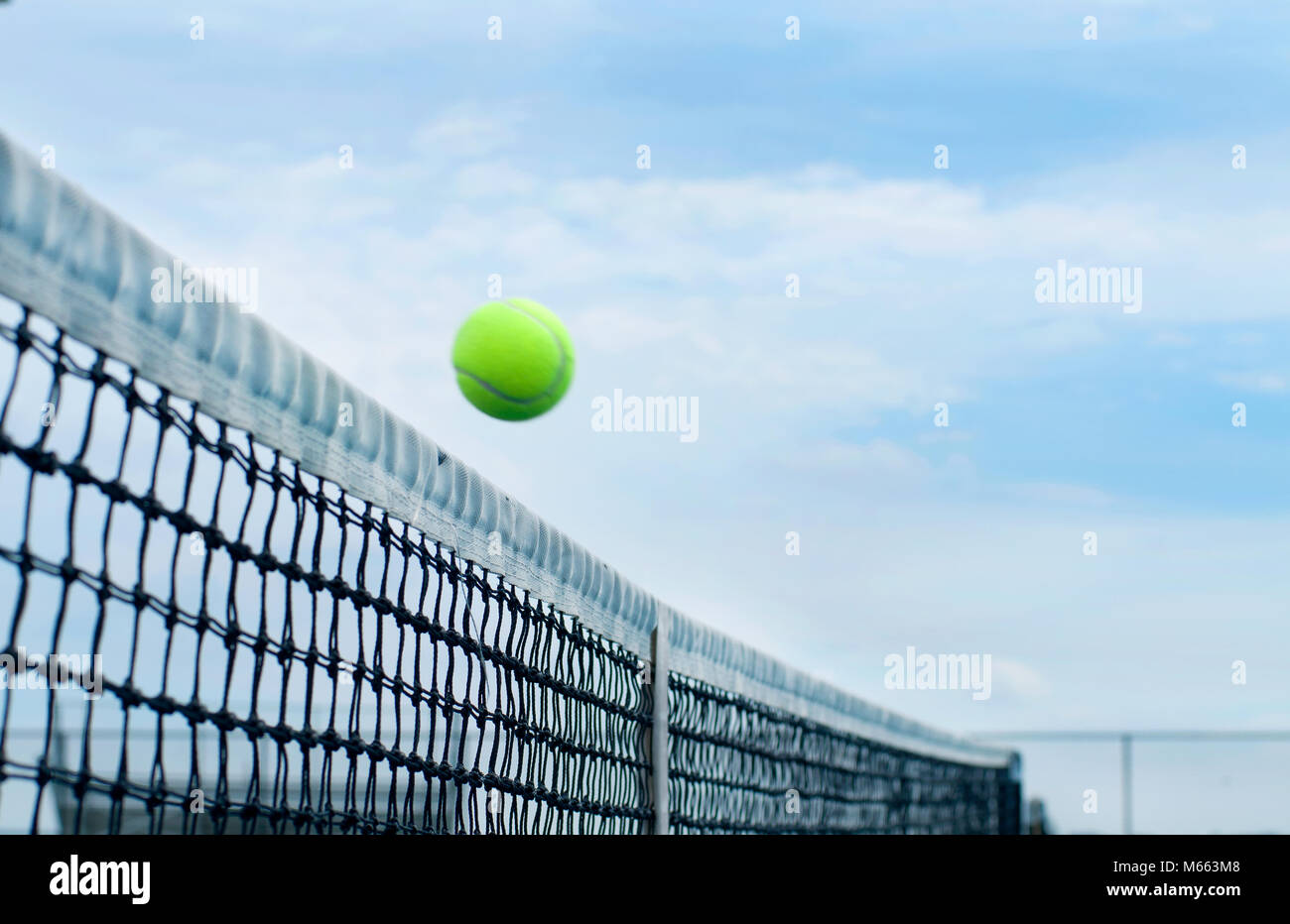 Tennis ball flying over middle net court on background blue sky. Tennis ...